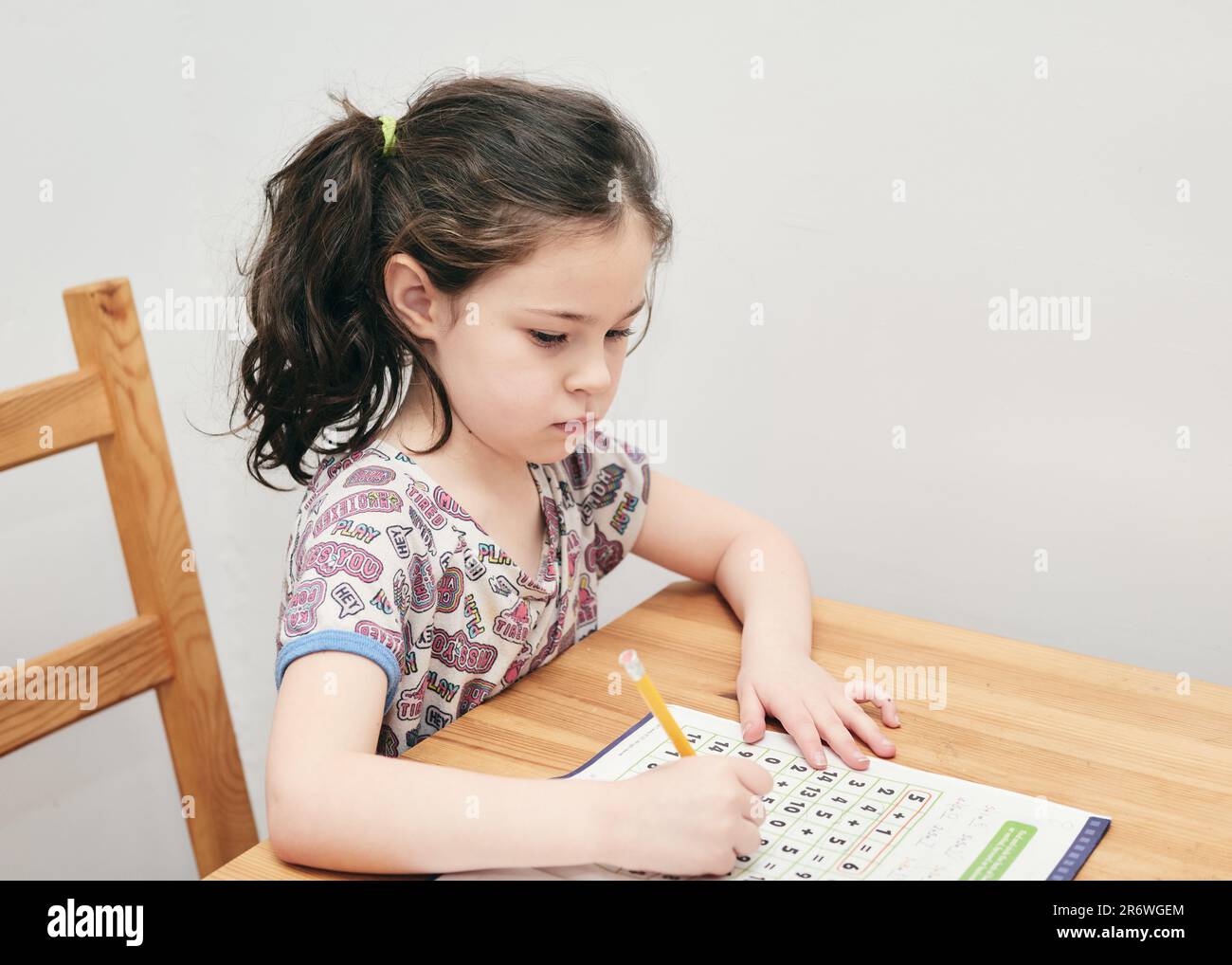 cute girl solving math puzzles at the kitchen table Stock Photo - Alamy