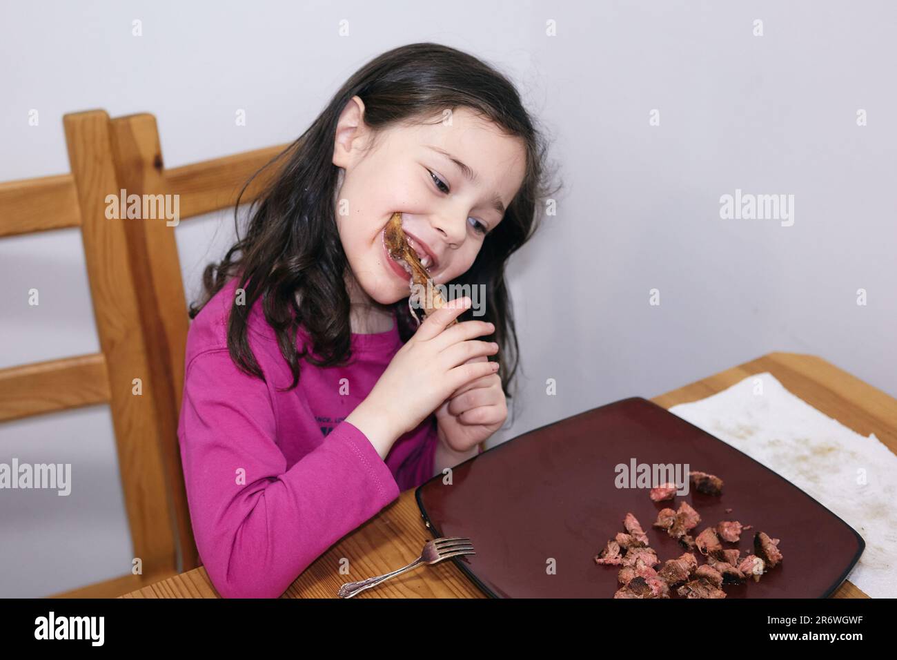 young girl with changing teeth working on a huge pork rib Stock Photo ...