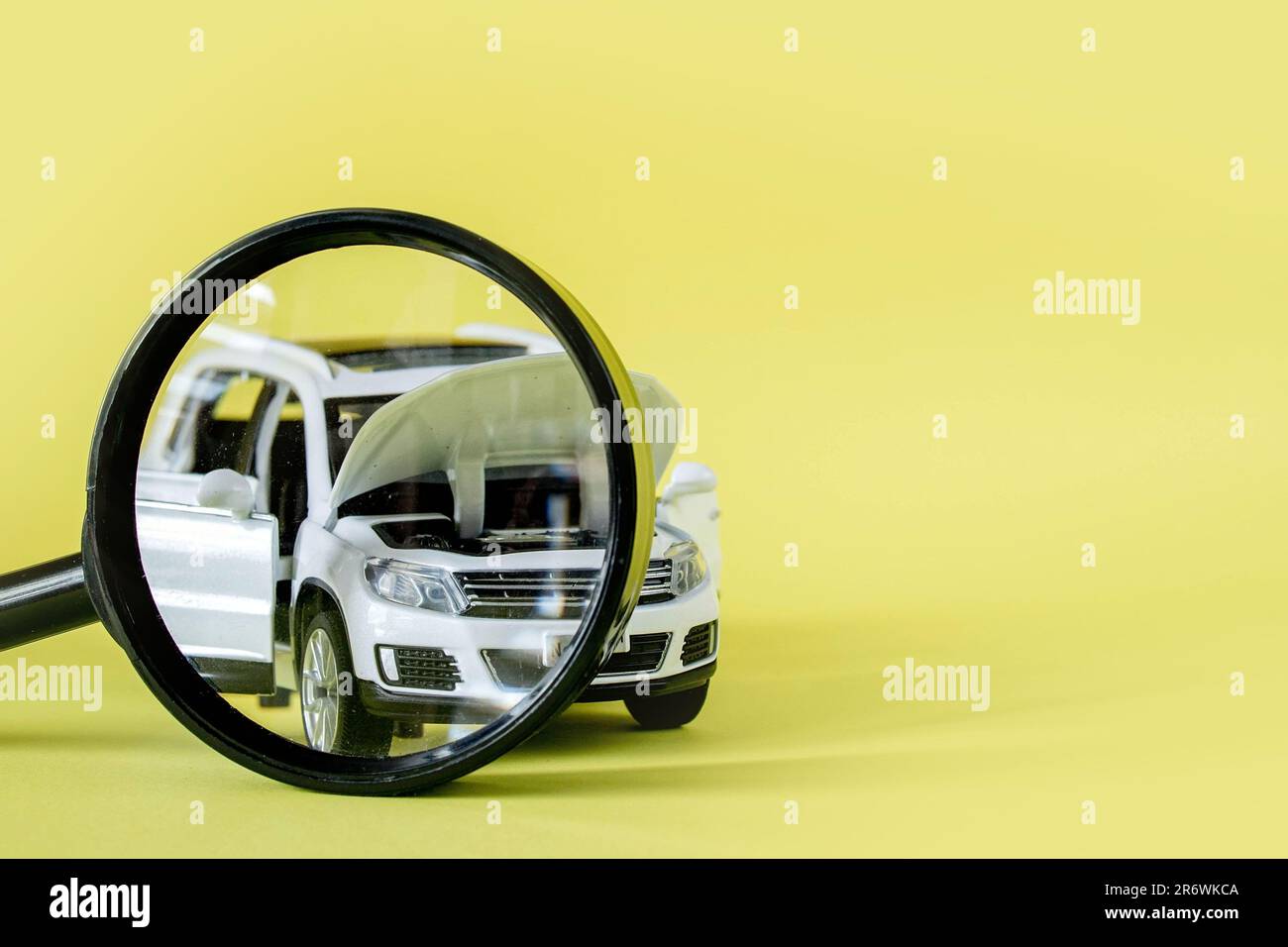 White car and magnifying glass on yellow background with copy space ...