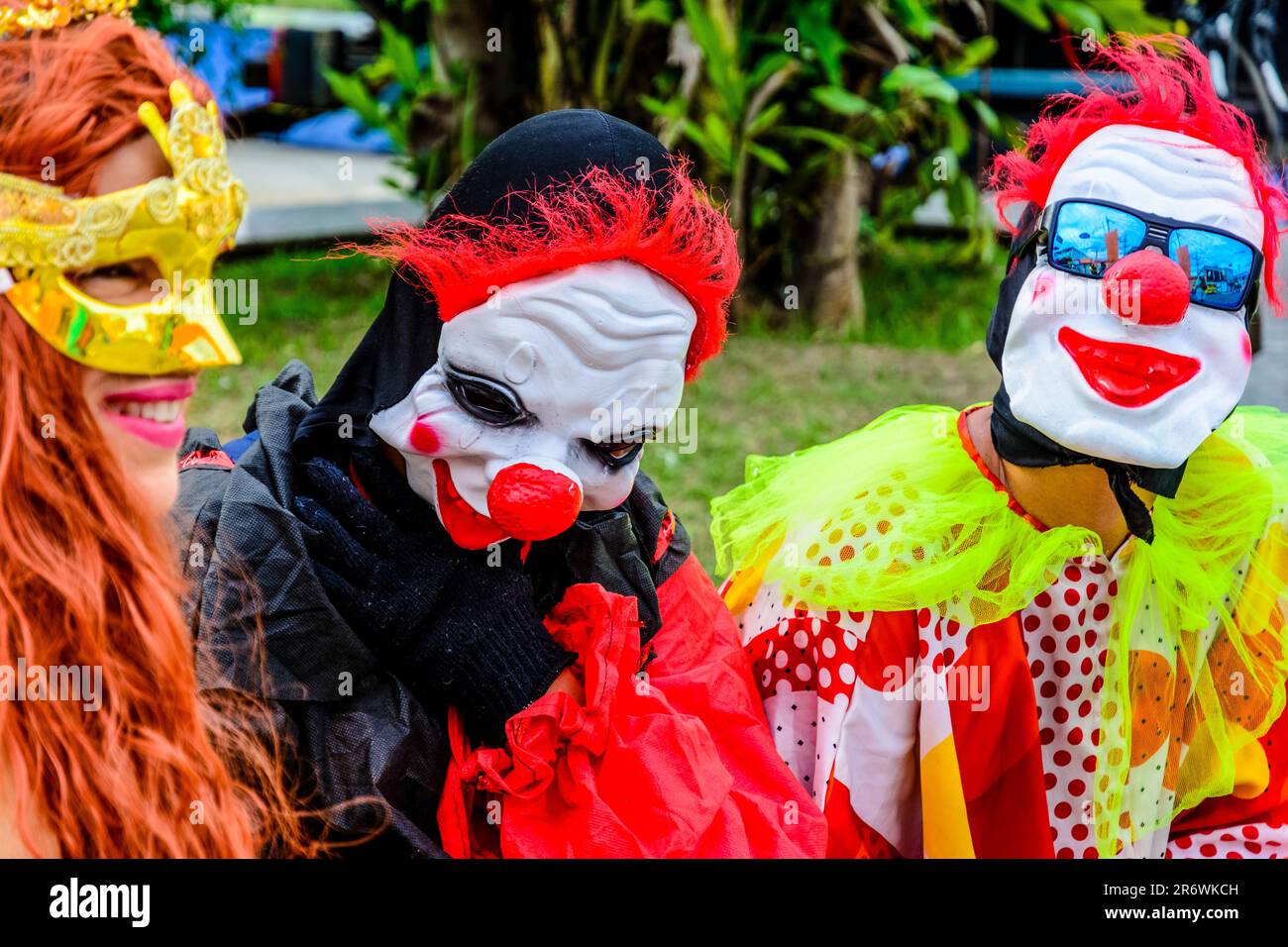 Three cheerful masked people in colorful costumes during a carnival in ...