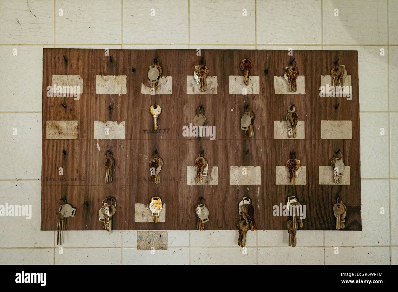 An aged wooden peace with several metal keys attached to it with small ...