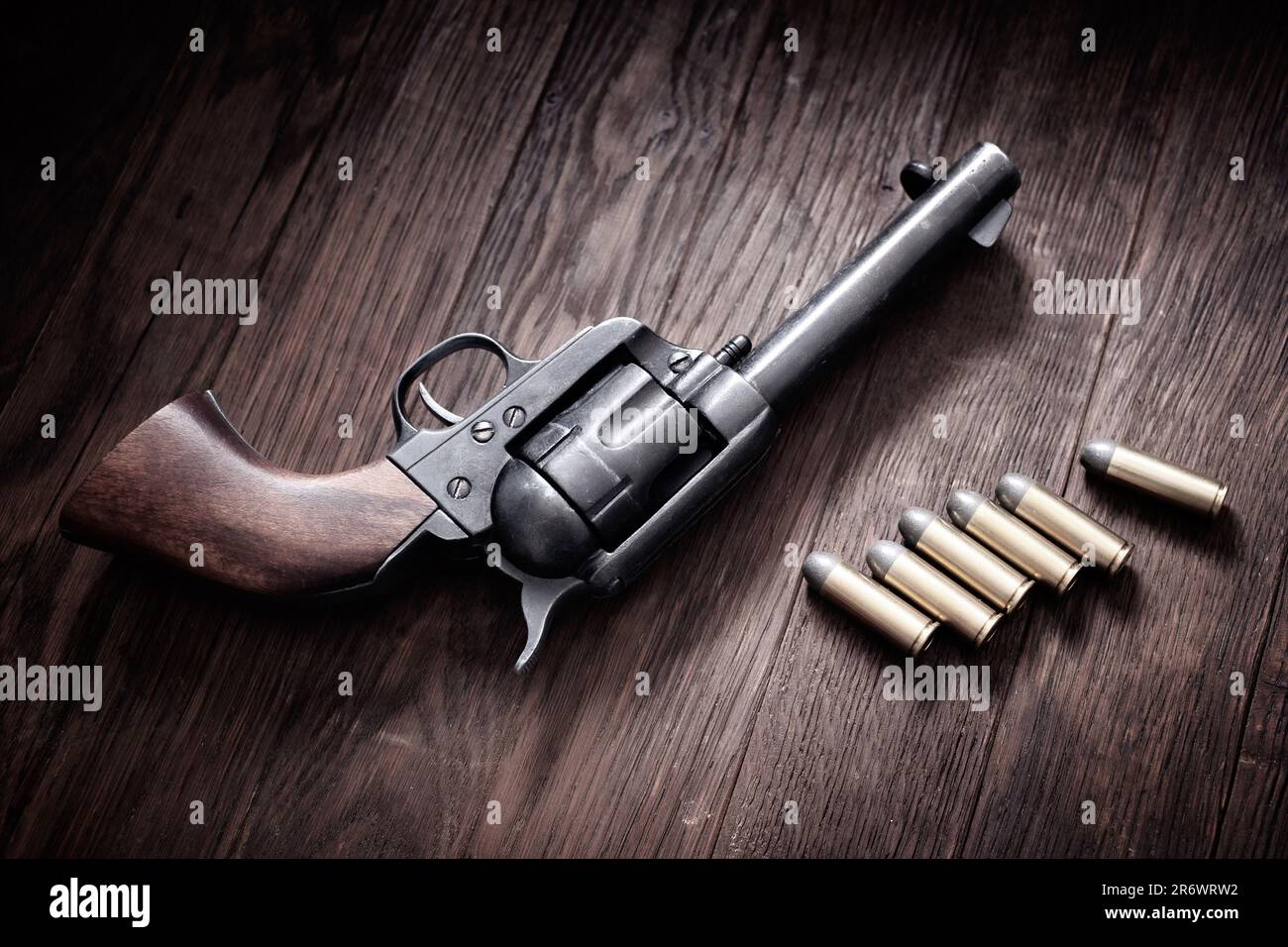 Old western revolver with cartridges on wooden table Stock Photo - Alamy