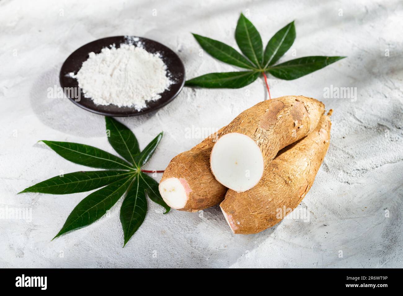 pile of cassava root and cassava flour on a gray and white textured ...