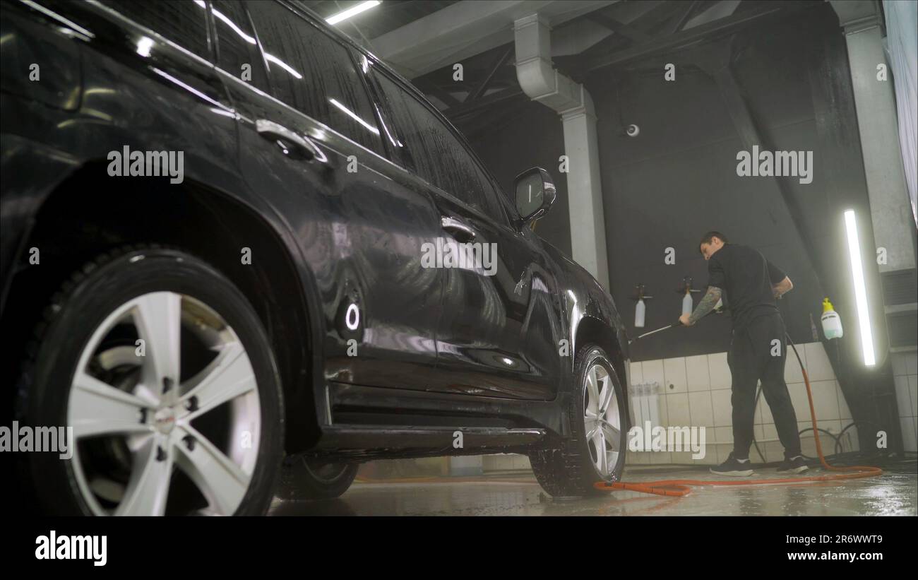 Man worker washing car's alloy wheels on a car wash. Luxury car wash ...