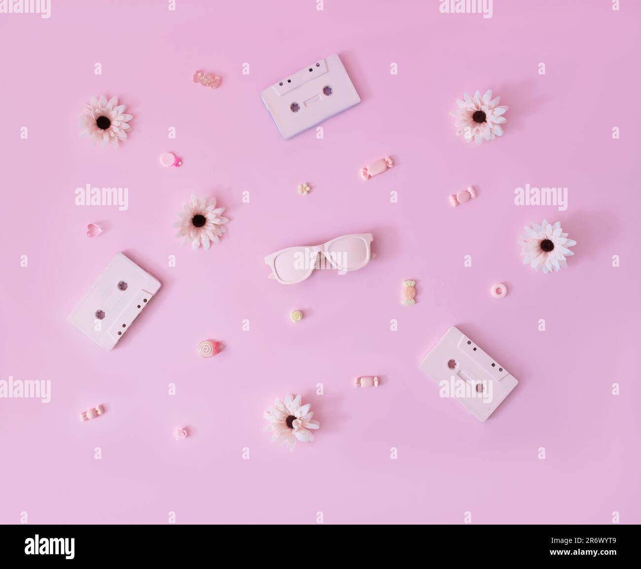 A wallpaper made of pink audio tapes, flowers, candies and sunglasses ...