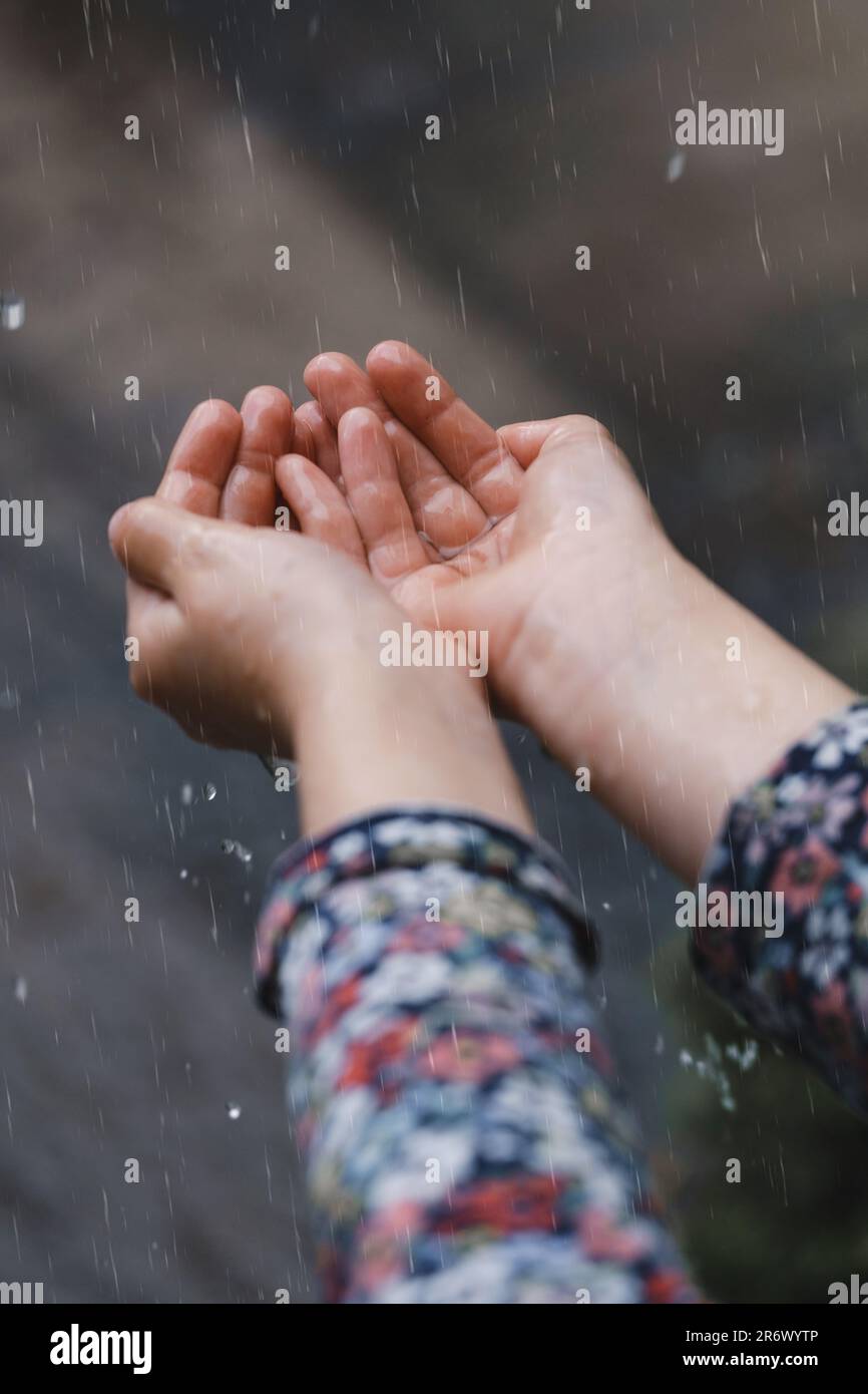 kids hands catching raindrops, weather concept. Closeup of rain falling ...