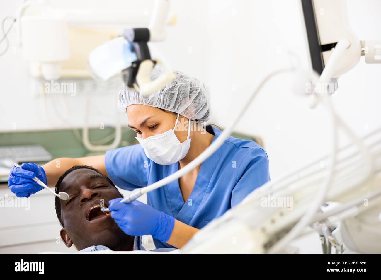 Dentist professional filling teeth for man patient sitting in chair ...