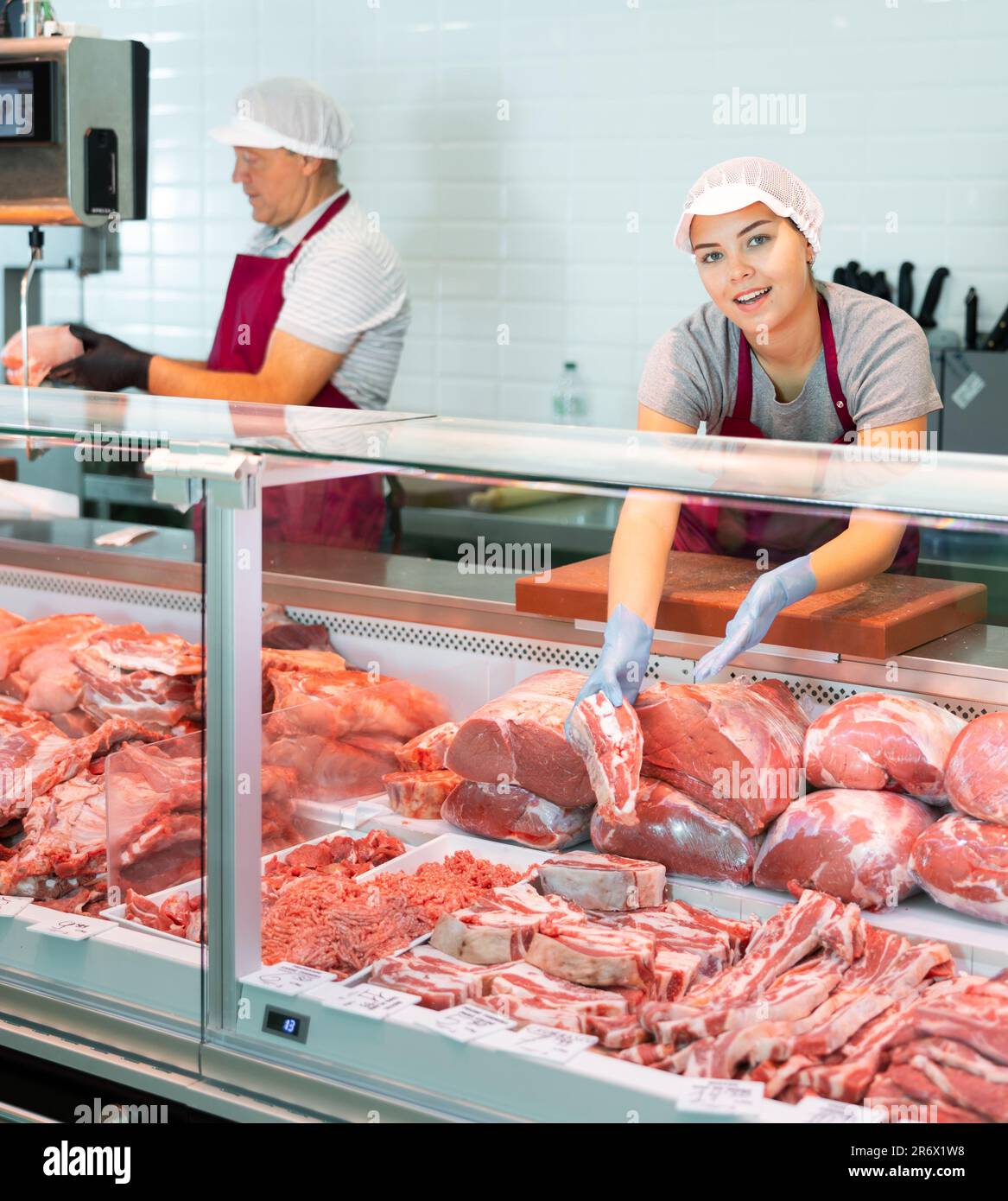 Young female butcher showing raw veal loin slices in butchery Stock ...