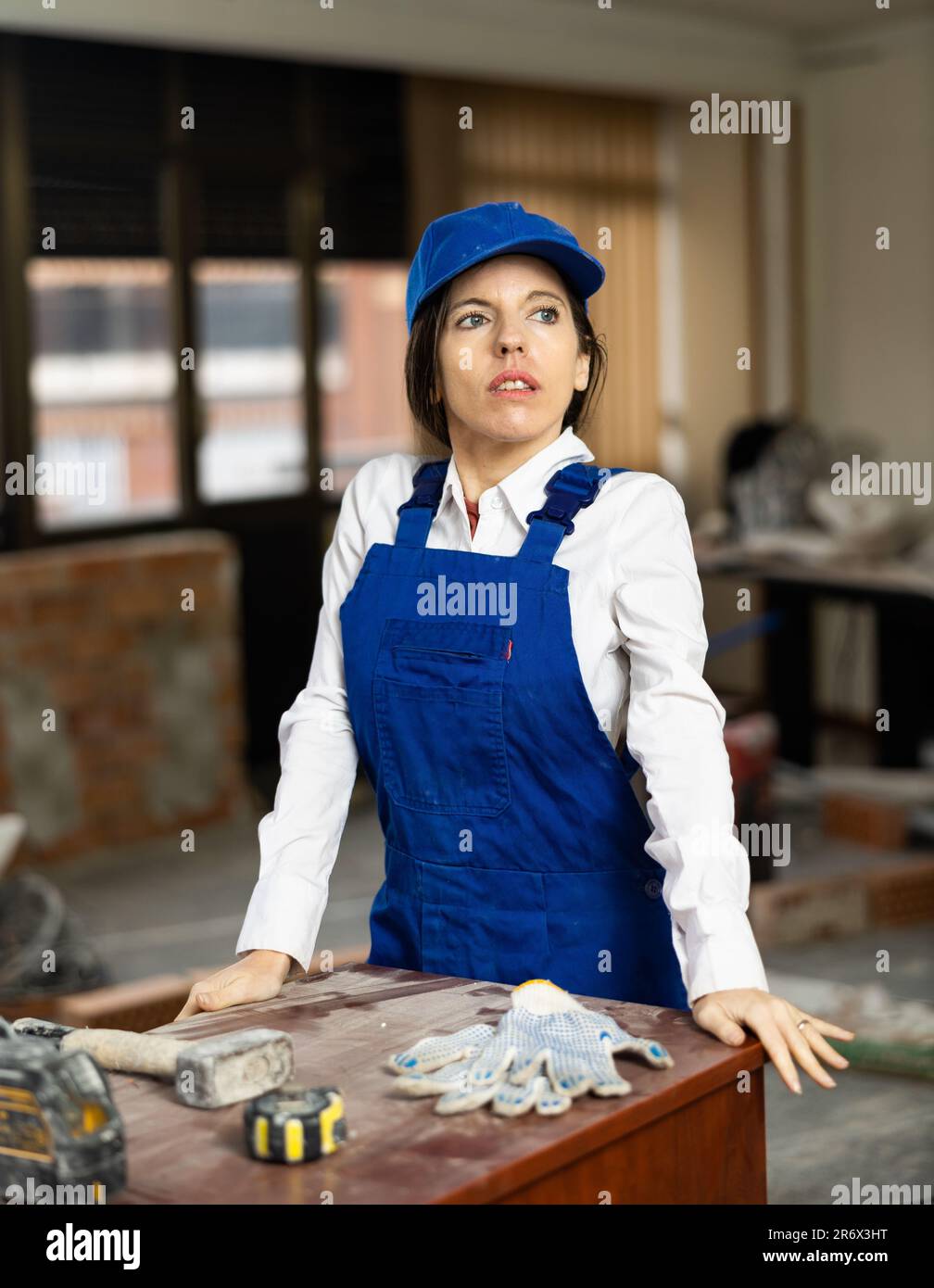 Woman foreman in blue overalls posing in house under construction Stock ...