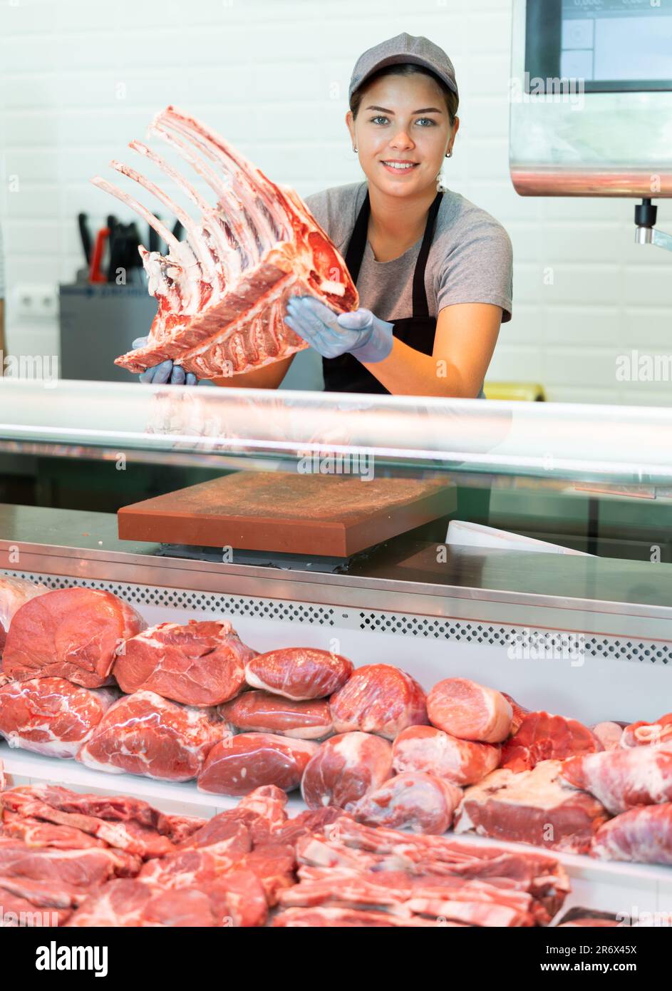Butcher shop salesgirl holding slab of raw beef ribs for tomahawk steak ...