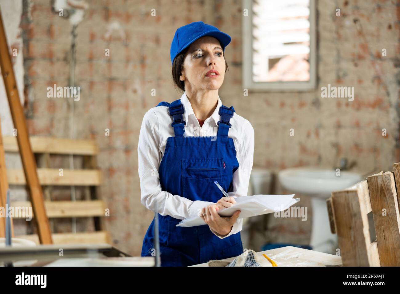 Female worker filling documentation while standing in apartment during ...
