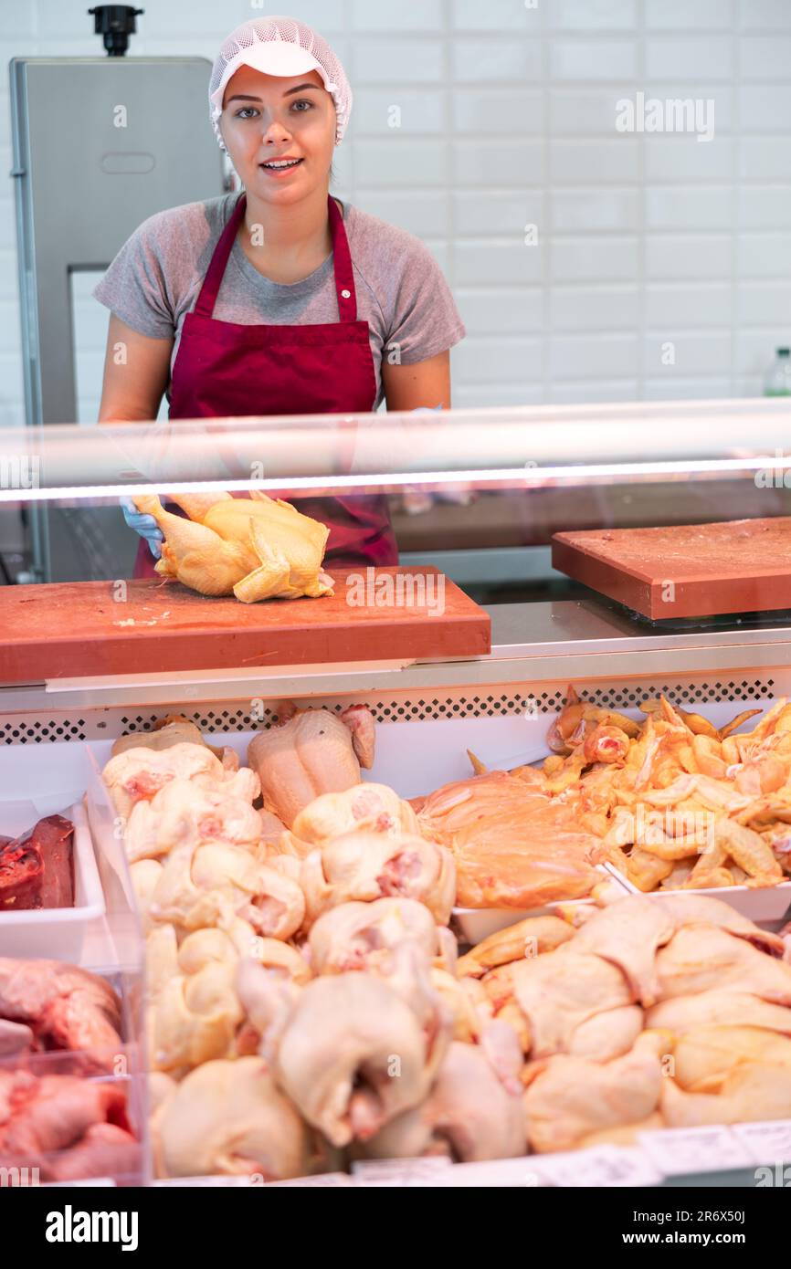 Young saleswoman laying raw broiler chickens in display case Stock ...