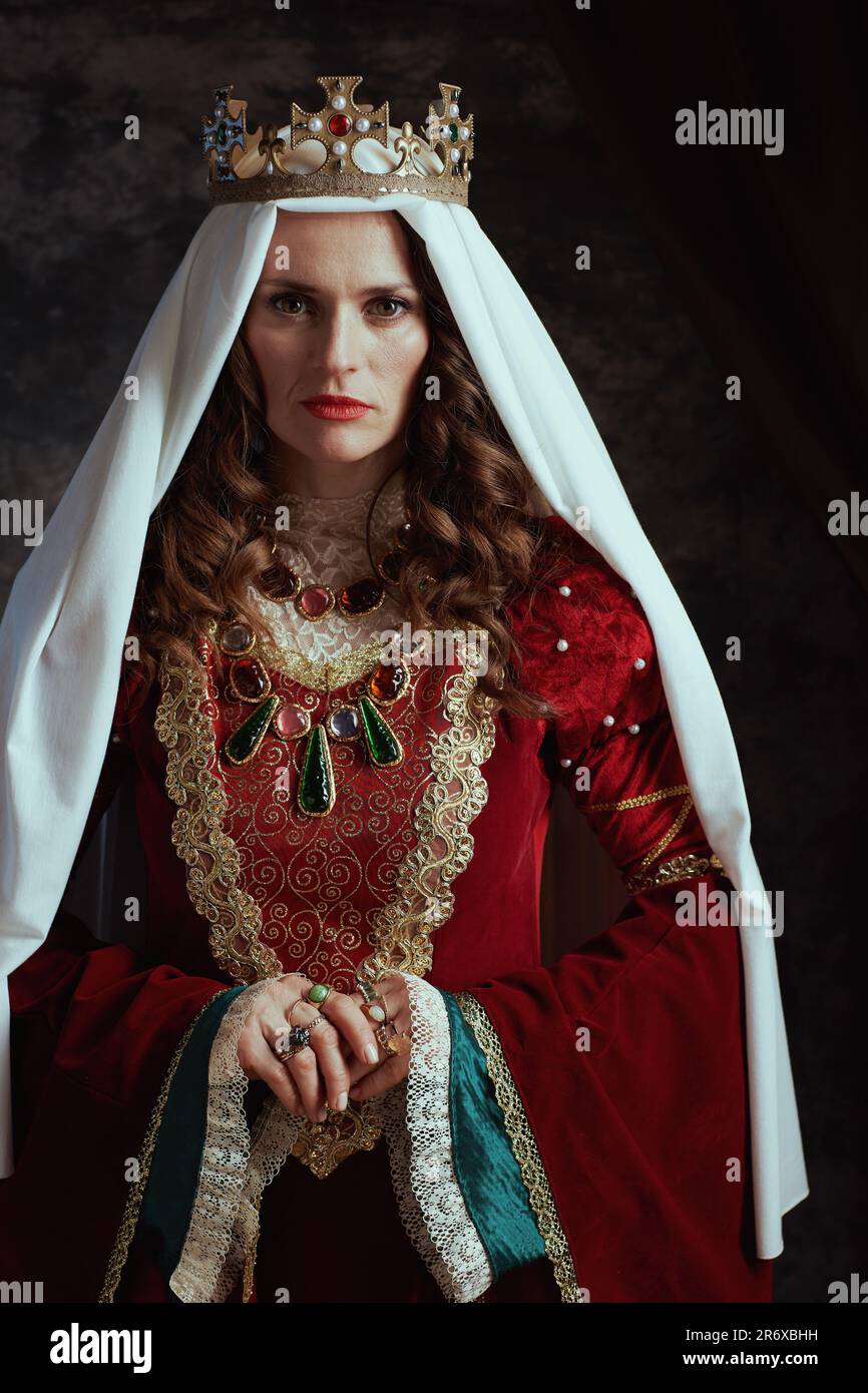 medieval queen in red dress with veil and crown on dark gray background ...
