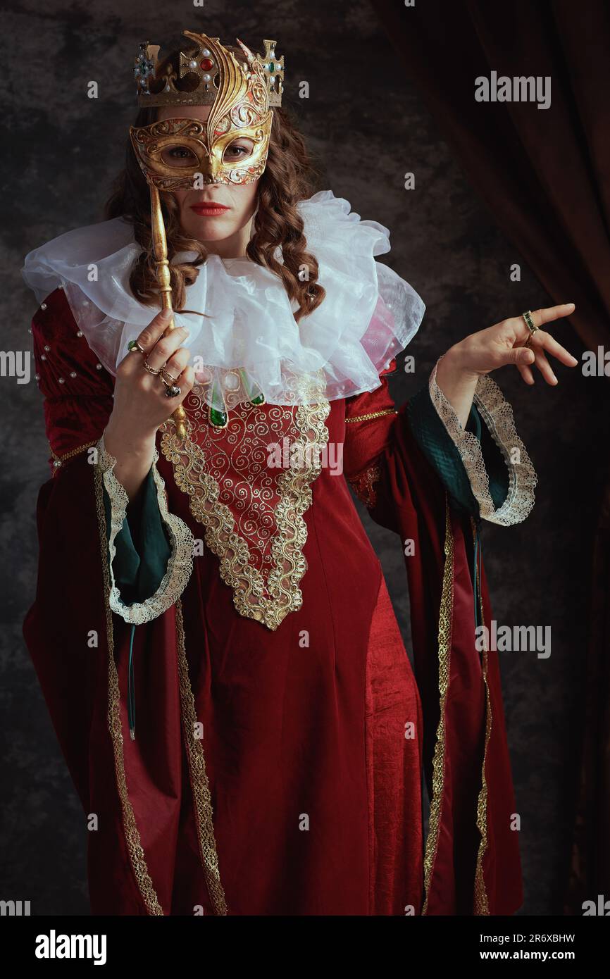 medieval queen in red dress with venetian mask, white collar and crown ...