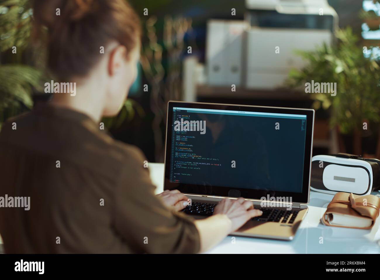 Seen from behind modern woman with laptop developing program in modern ...