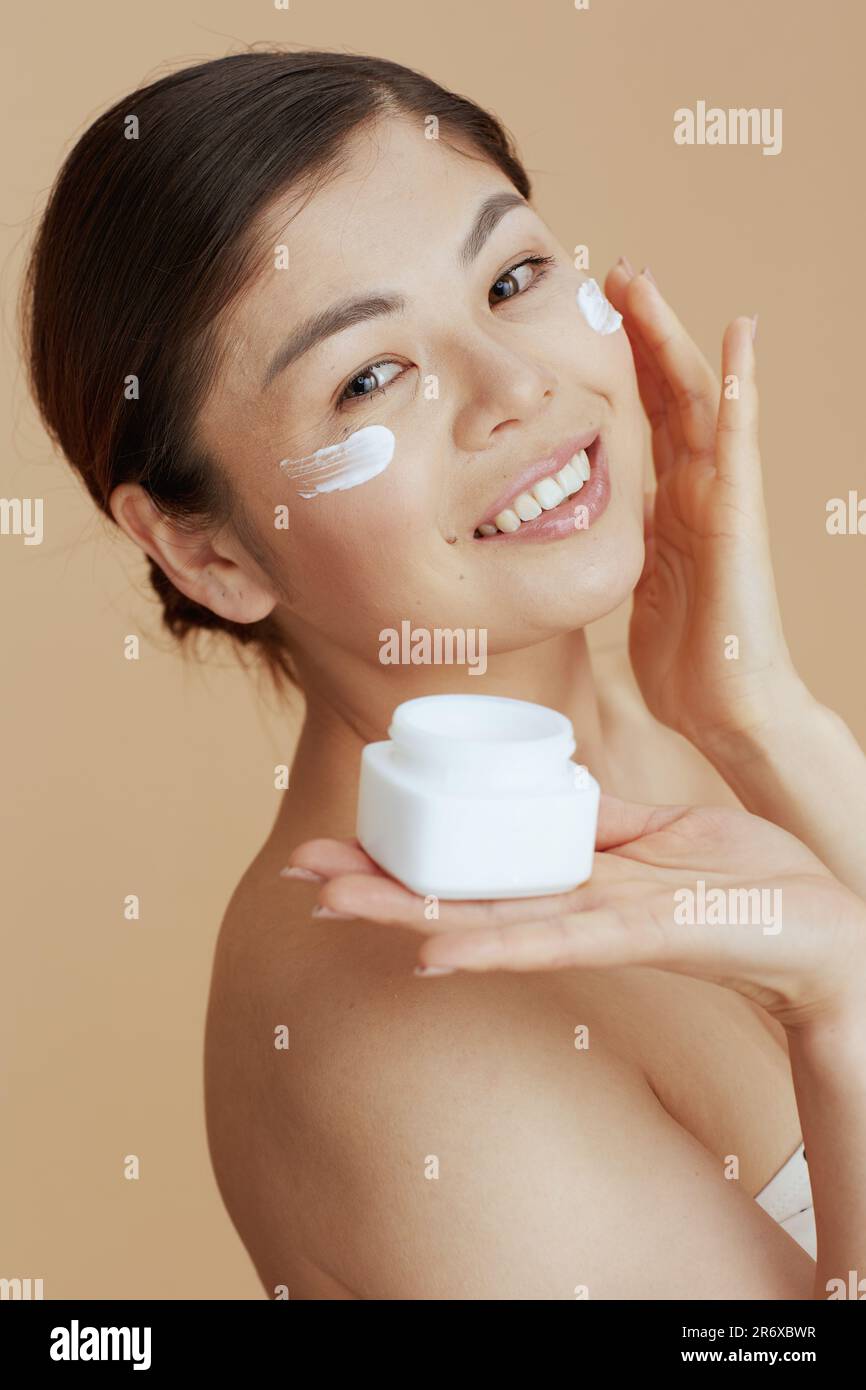 modern asian woman with facial cream jar and facial cream on face ...