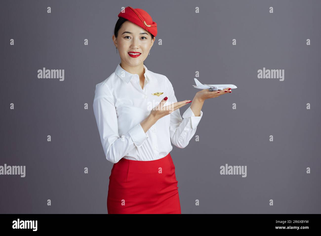 happy stylish asian female air hostess in red skirt and hat uniform ...