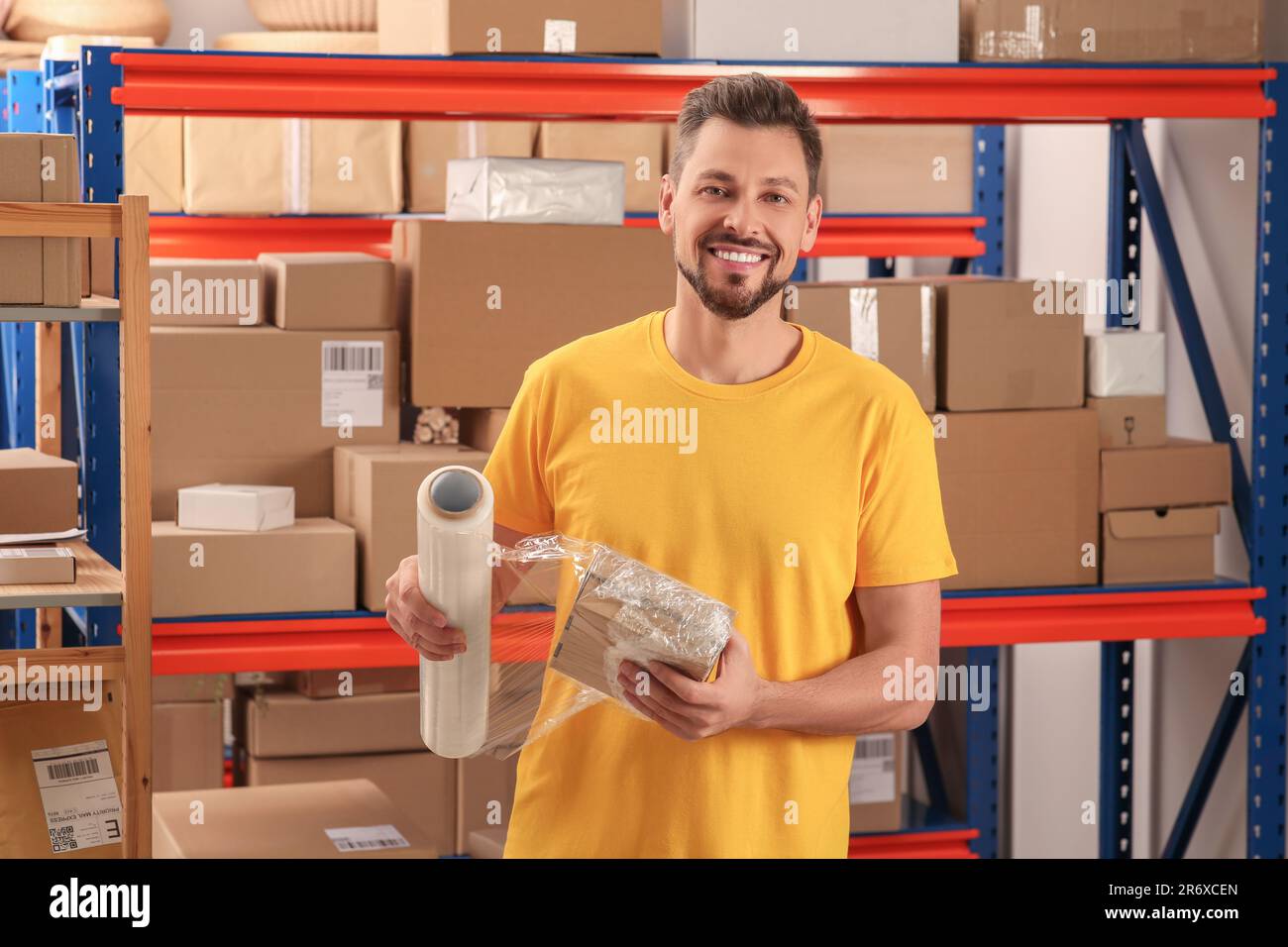 Post office worker wrapping parcel in stretch film indoors Stock Photo ...