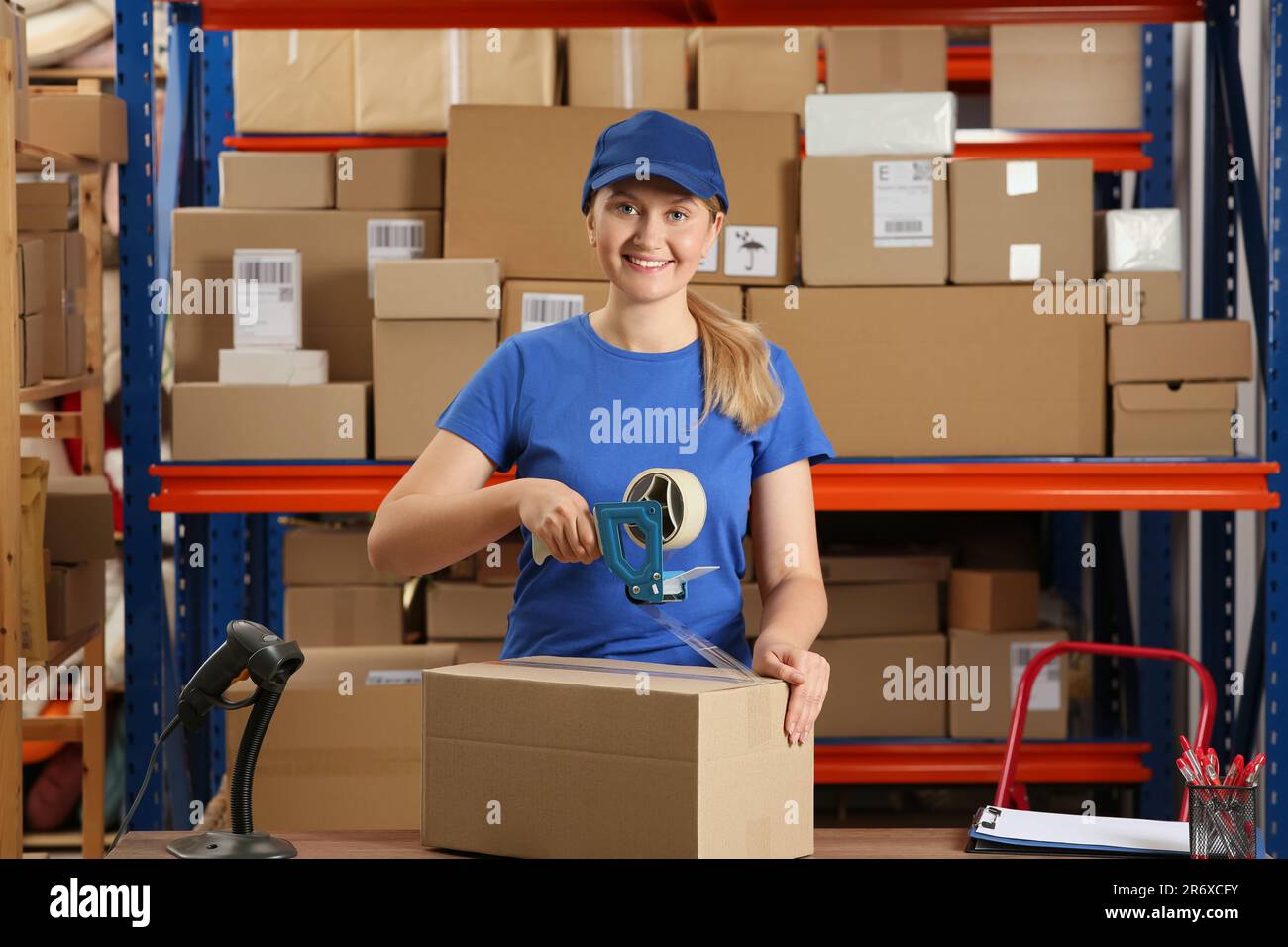 Post office worker packing parcel near rack indoors Stock Photo - Alamy