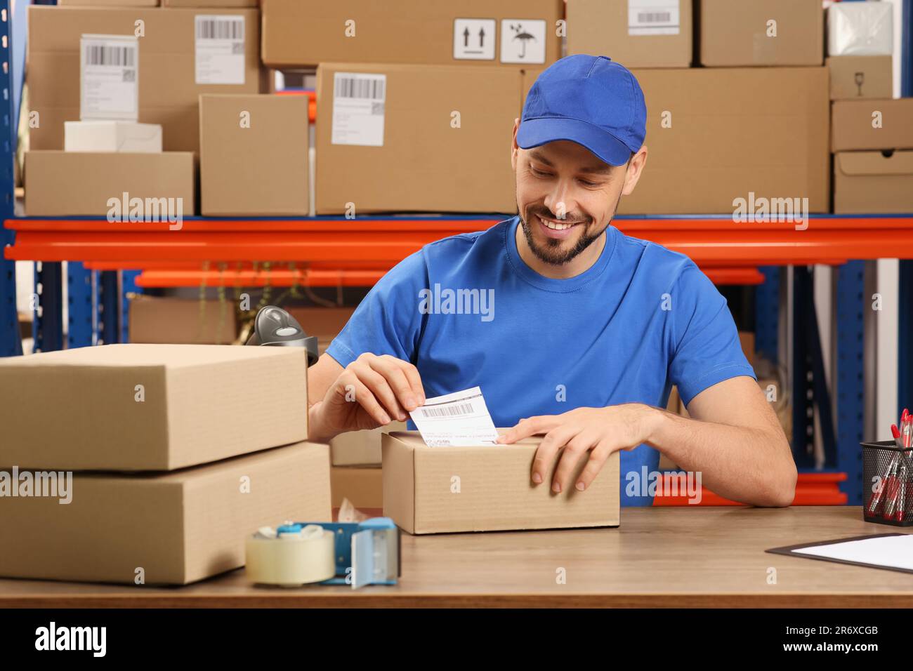 Post office worker sticking barcode on parcel at counter indoors Stock ...