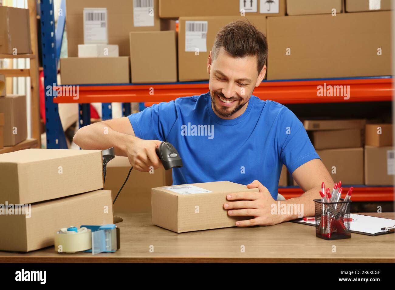 Post office worker with scanner reading parcel barcode at counter ...