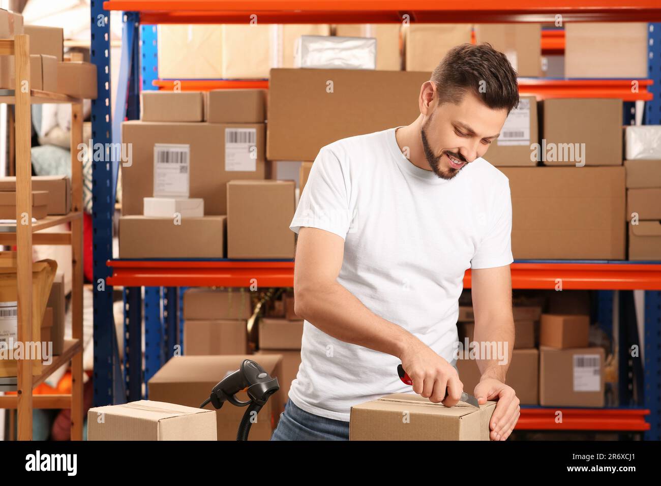 Post office worker with utility knife opening parcel indoors Stock ...