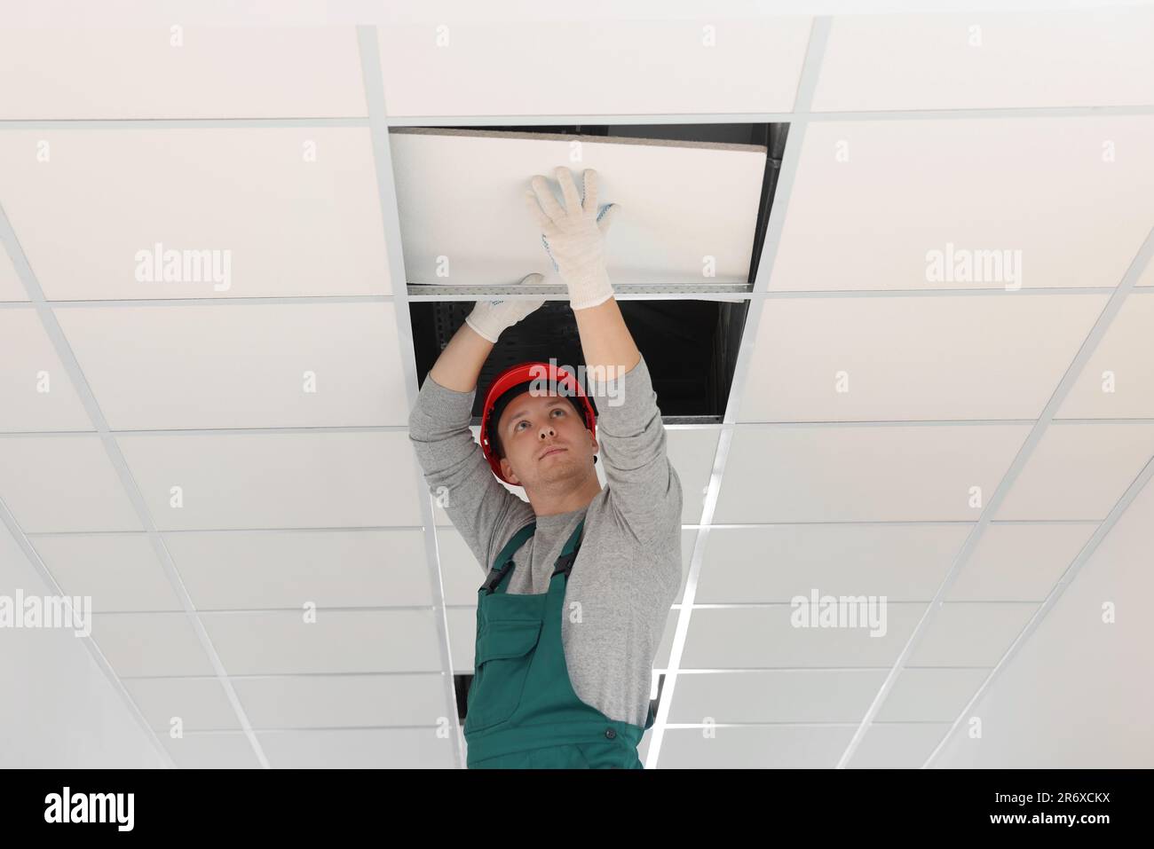 Suspended ceiling installation. Builder working with PVC tile Stock ...