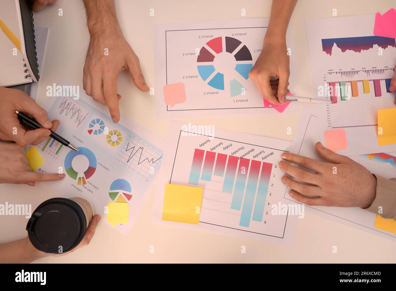 Office employees with different charts at white table, top view. Team ...
