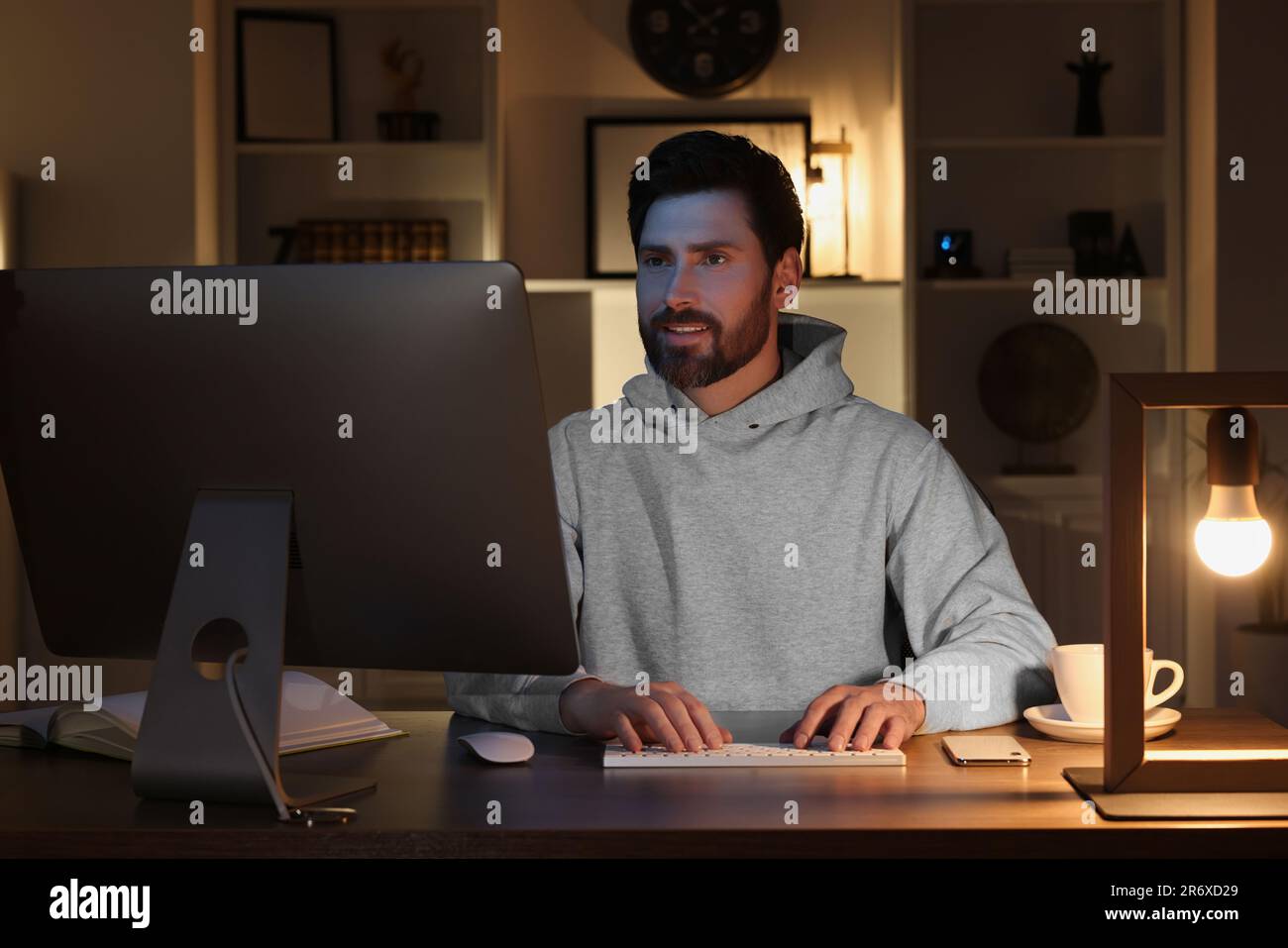 Home workplace. Man working with computer at wooden desk in room at ...