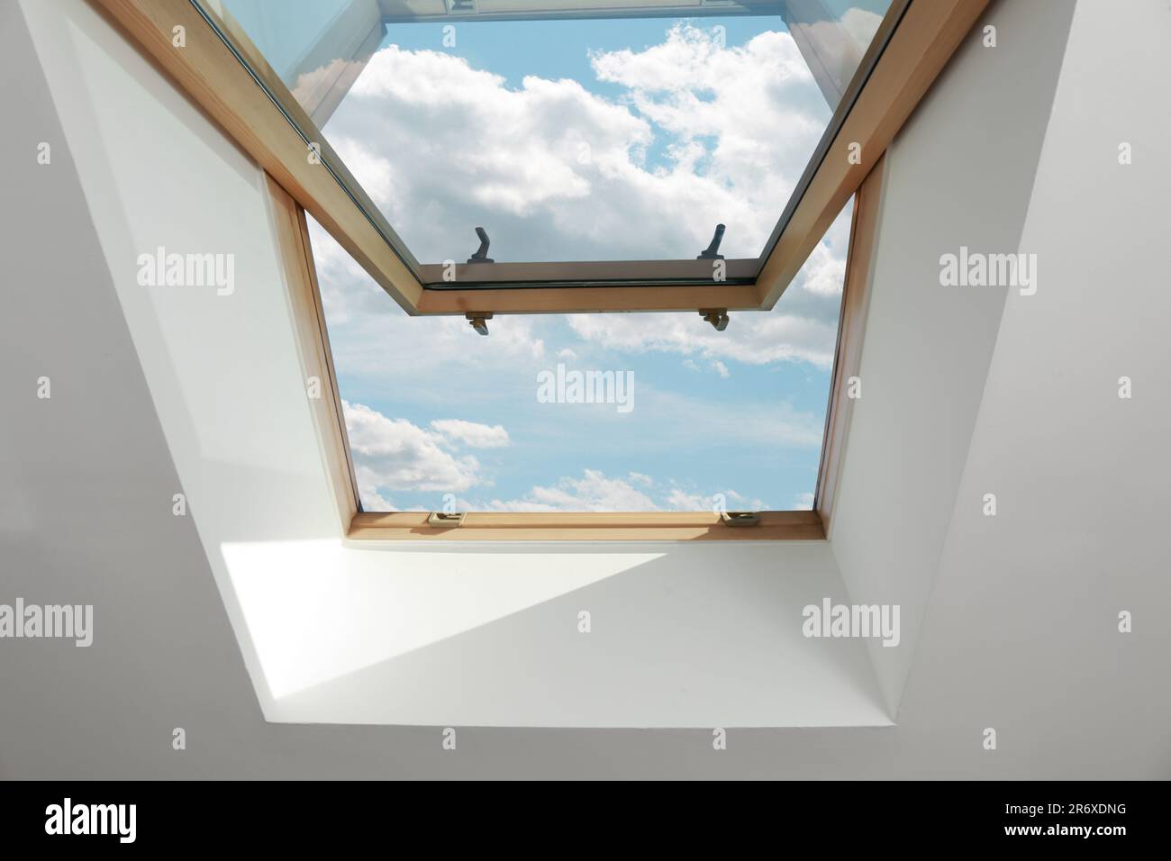 Open skylight roof window on slanted ceiling in attic room, bottom view ...