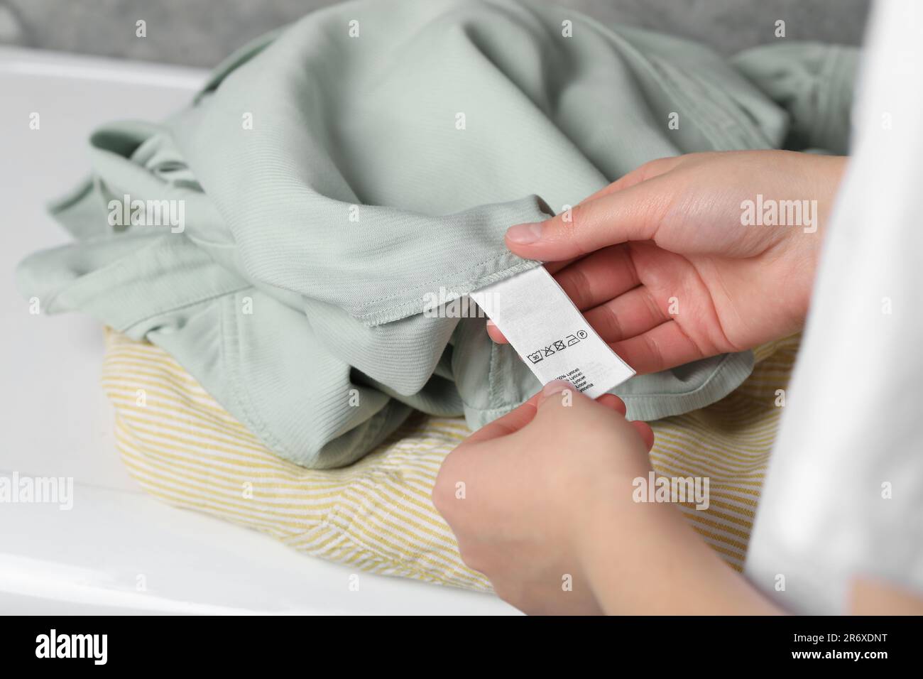 Woman reading clothing label with care symbols and material content on ...