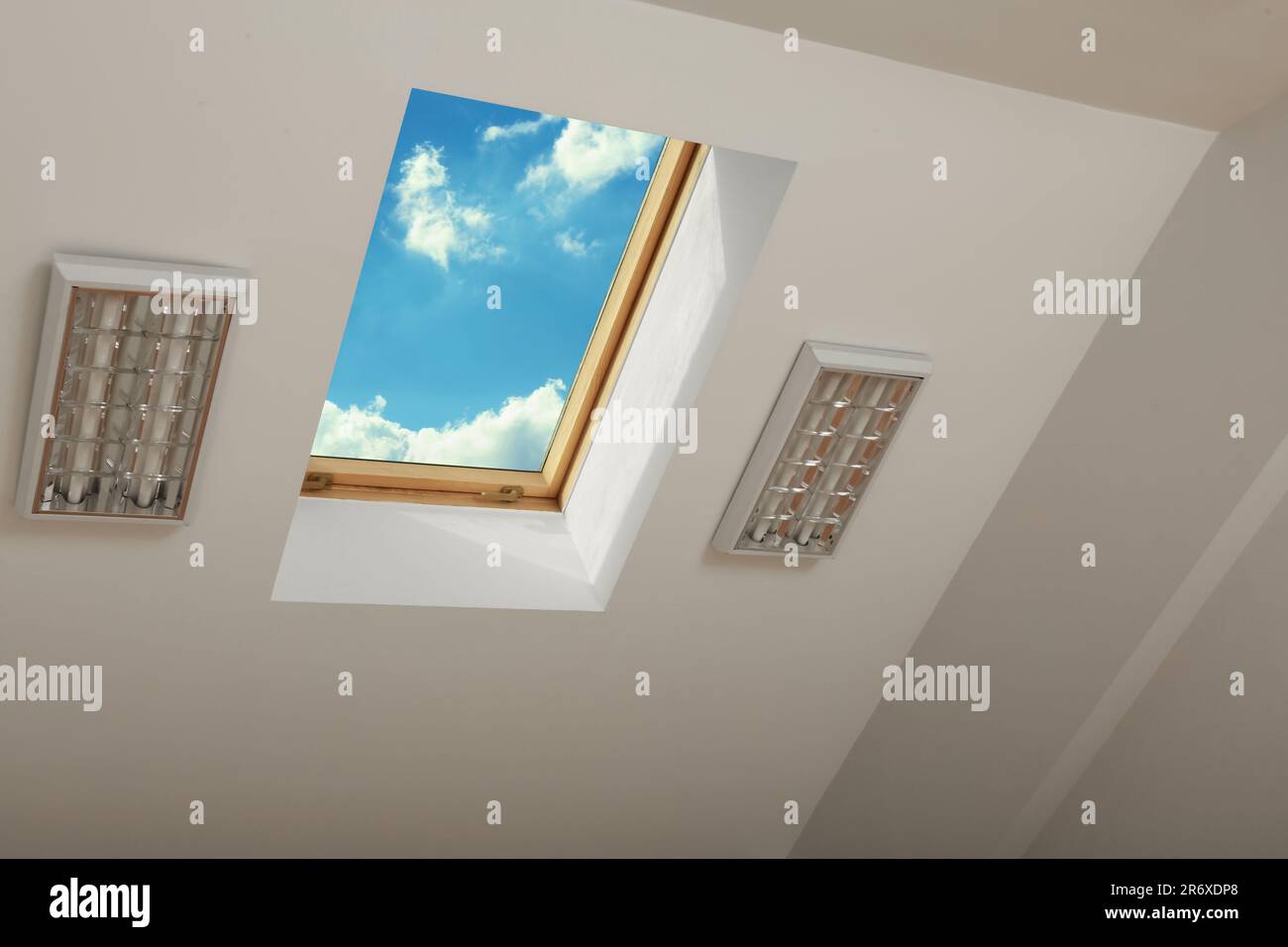 Skylight roof window and lamps on slanted ceiling in attic room, bottom ...