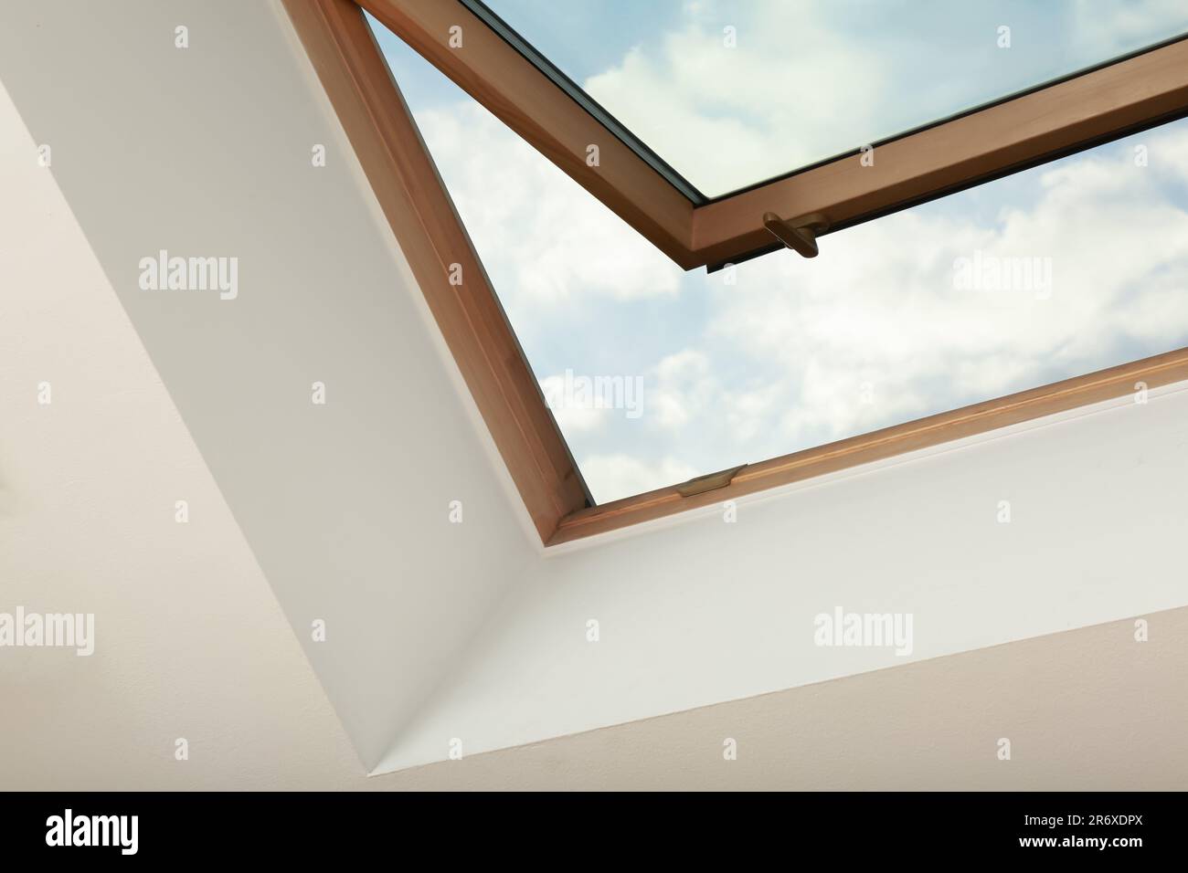 Open skylight roof window on slanted ceiling in attic room, low angle ...