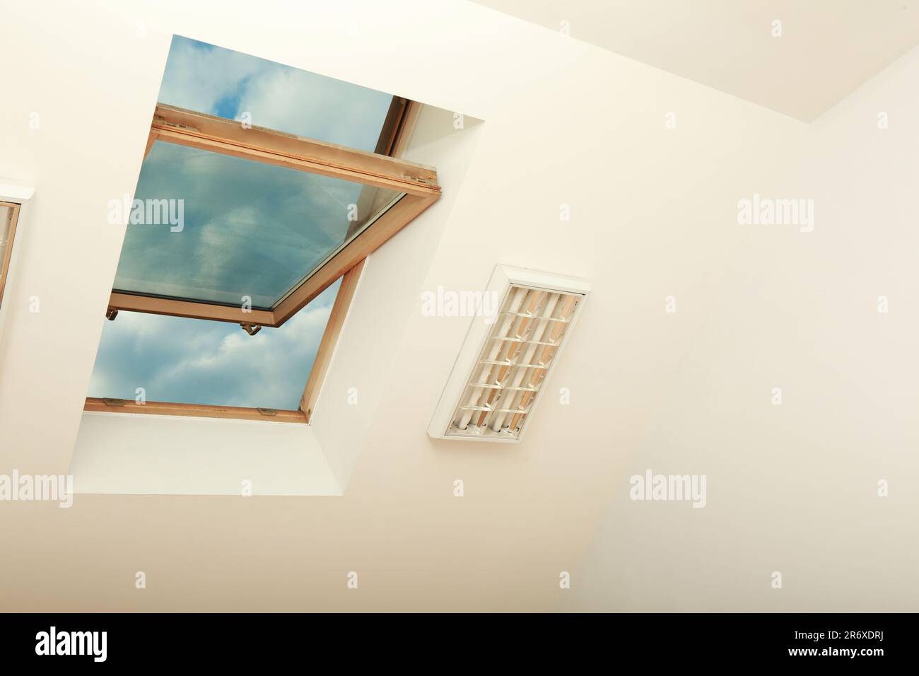 Open skylight roof window on slanted ceiling in attic room, low angle ...