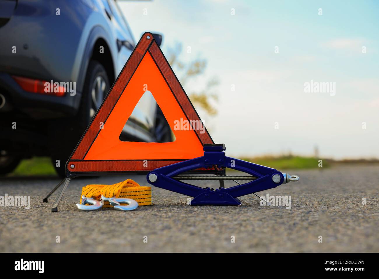 Emergency warning triangle, towing strap and scissor jack near car ...