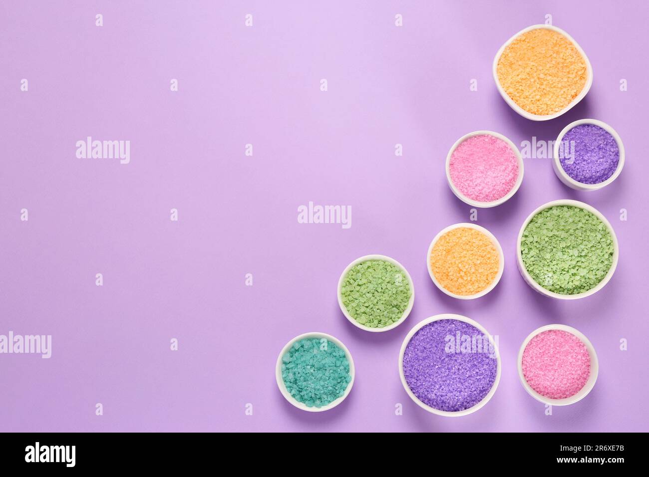 Different types of aromatic sea salt on purple background, flat lay ...