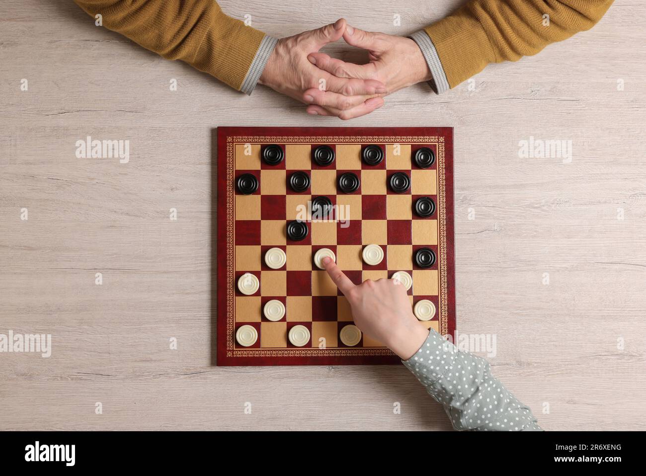 Senior man playing checkers with woman at white wooden table, top view ...