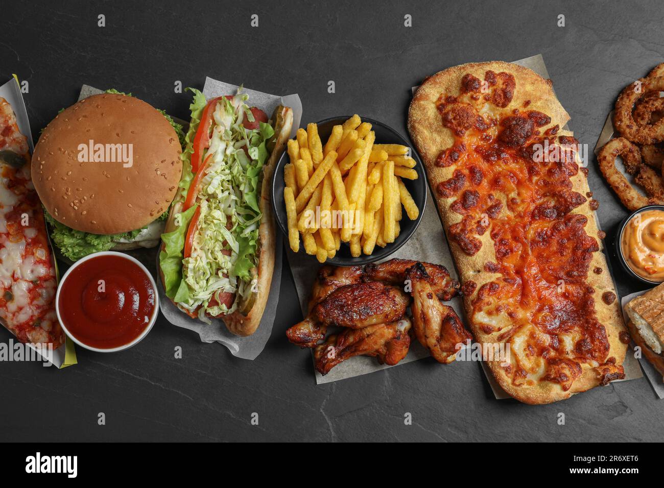 Burger, pizza and other fast food on black table, flat lay Stock Photo ...