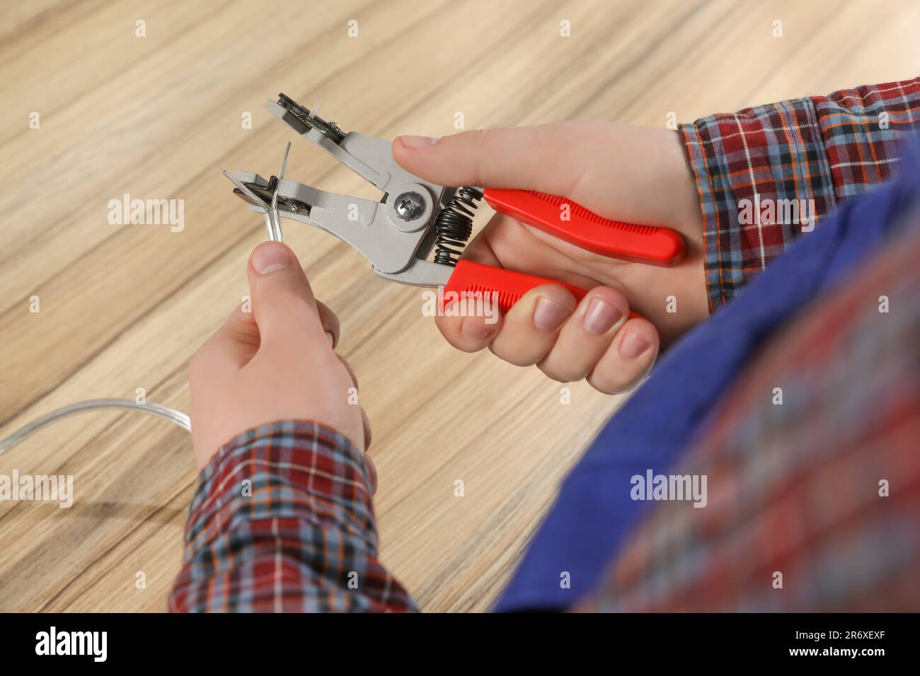 Professional electrician stripping wiring at wooden table, above view ...