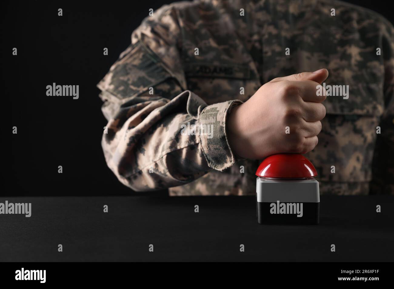 Serviceman pressing red button of nuclear weapon at black table ...