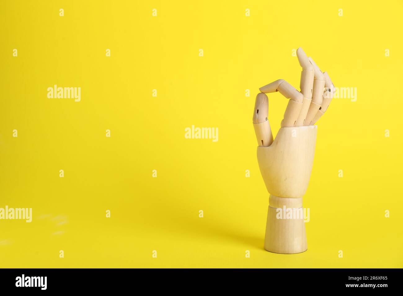 Wooden mannequin hand showing okay gesture on yellow background. Space ...
