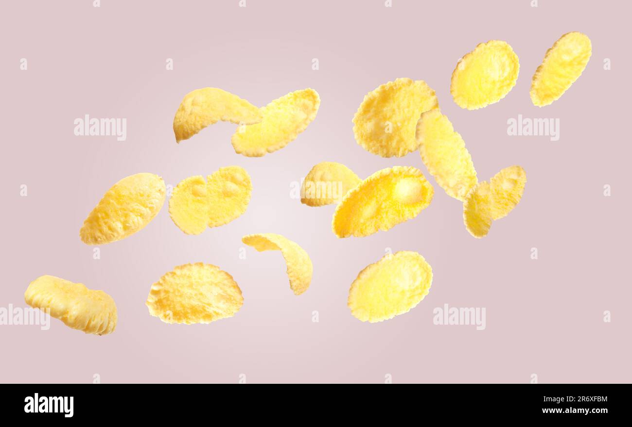 Many tasty corn flakes flying on pale light pink background Stock Photo ...