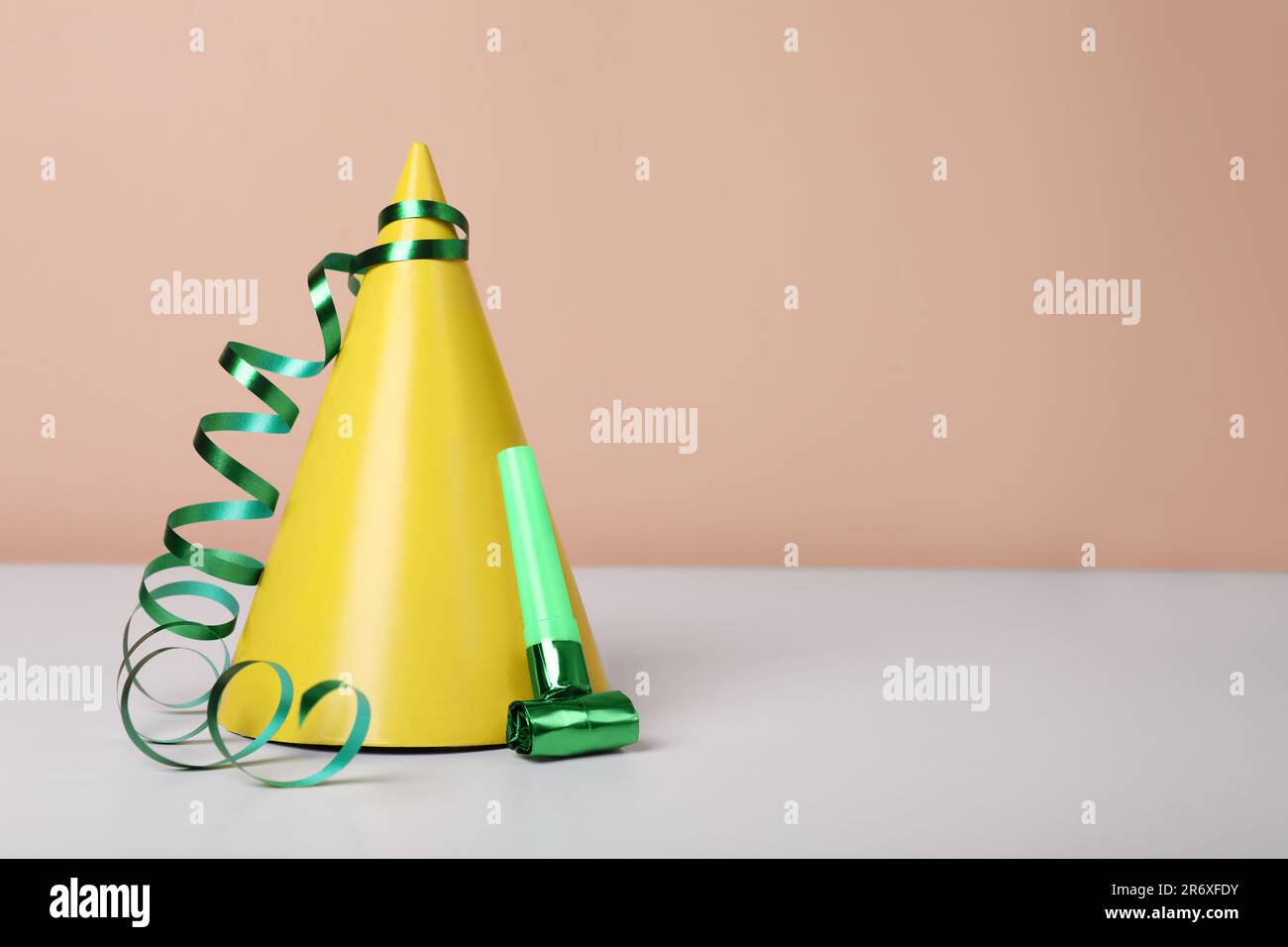 Colorful party hat, streamer and blower on white table, space for text ...