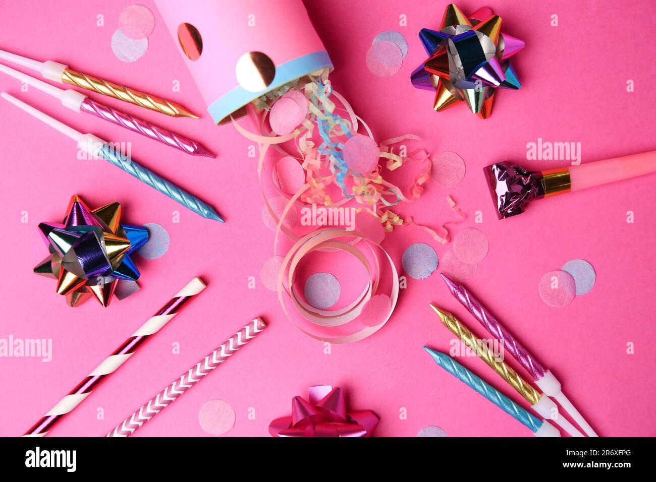 Party cracker and different festive items on bright pink background ...