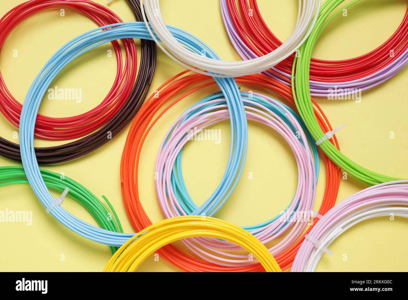 Colorful plastic filaments for 3D pen on pale yellow background, flat ...