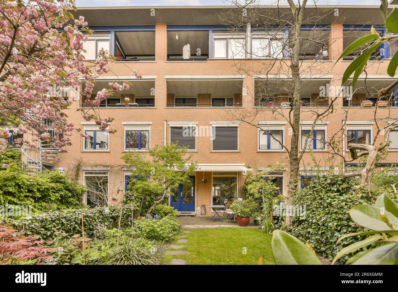 an apartment building with trees and bushes in the front yard, looking ...