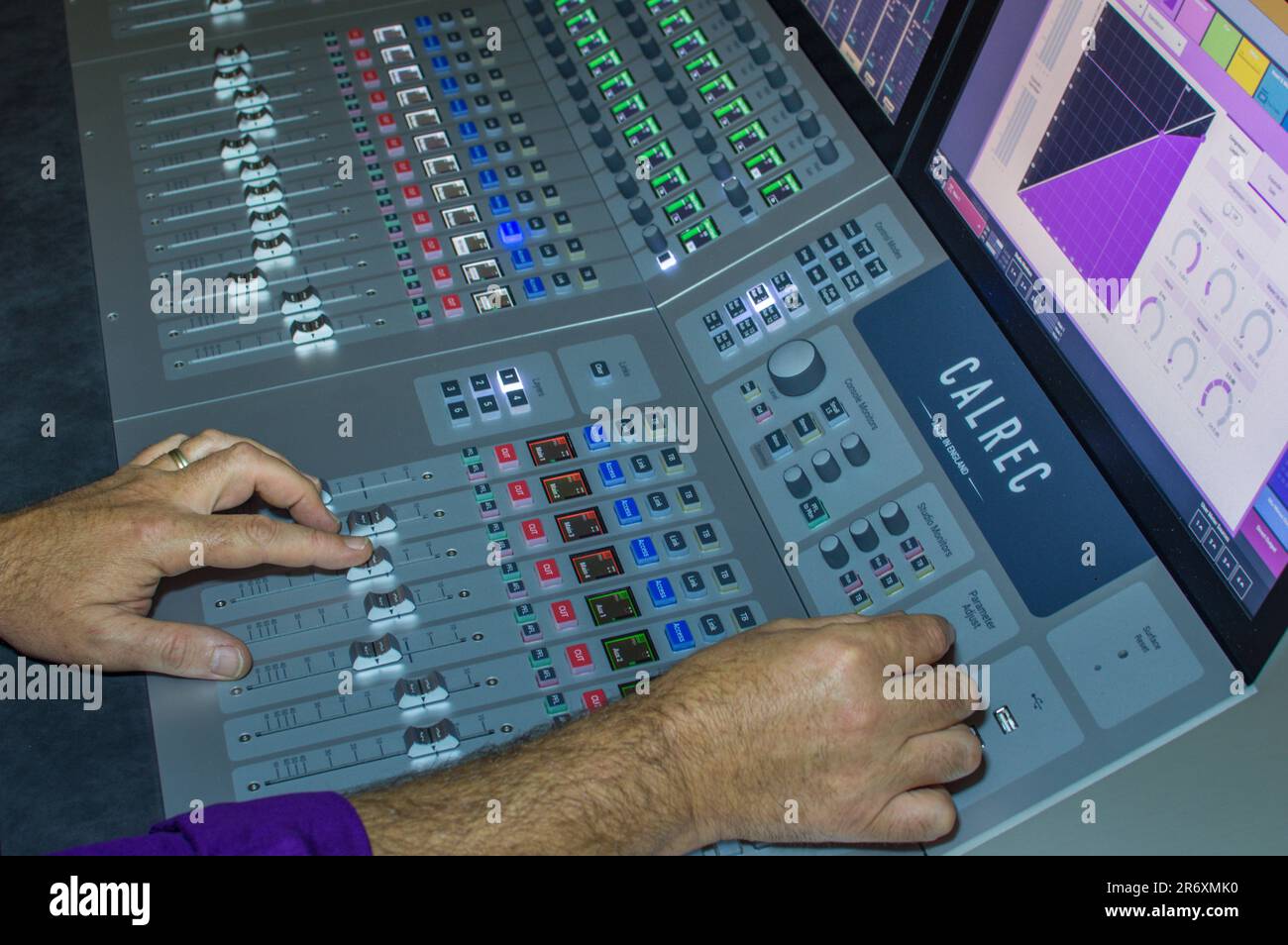 A sound engineer operates a Calrec Summa broadcast audio mixing console ...