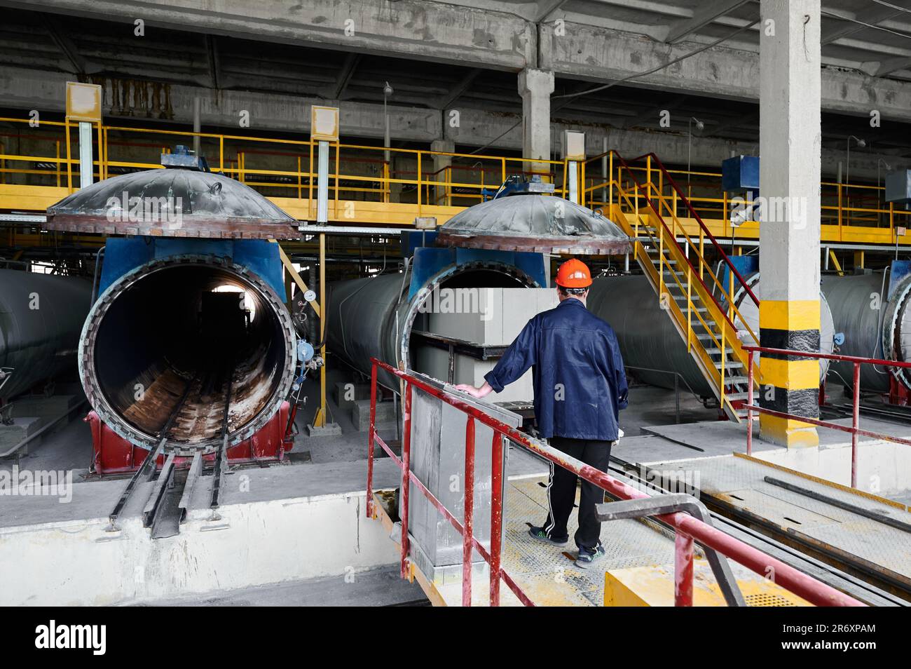 Worker loads raw blocks into open tanks for hardening Stock Photo - Alamy