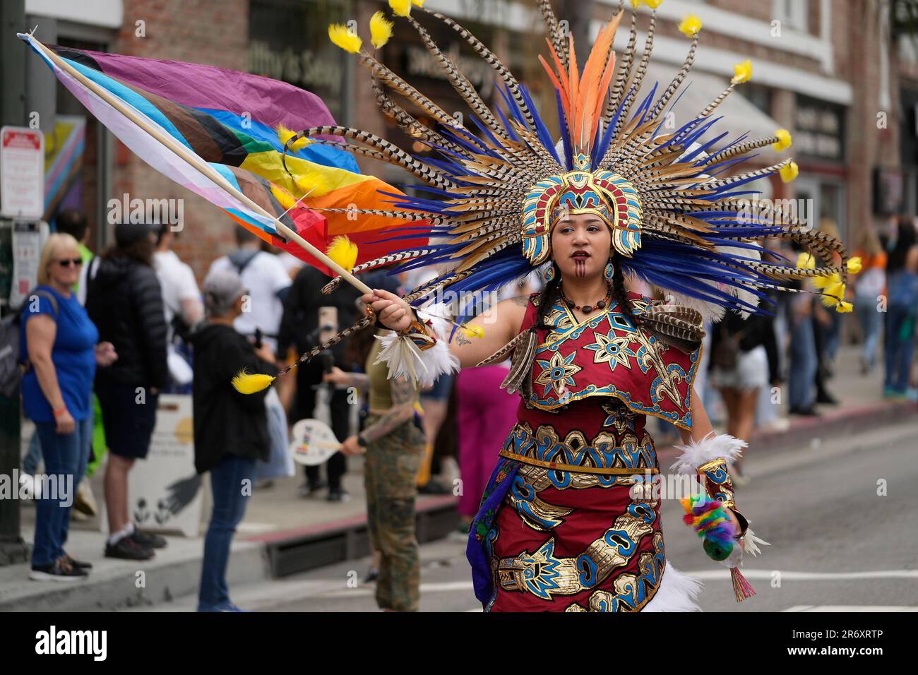 A member of the Aztec dancers flies a Pride flag at the LA Pride Parade ...