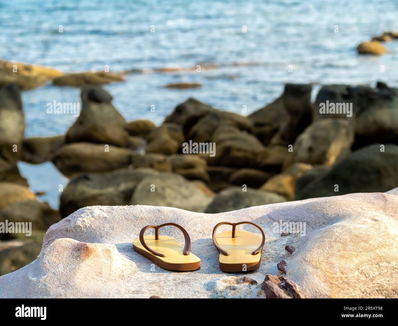 Empty yellow rubber a pair of sandals were taken off, on the rock at ...